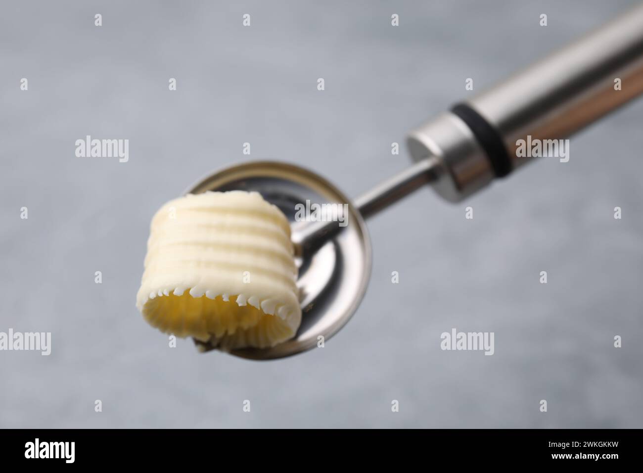 Tasty butter curl in spoon on light grey table, closeup Stock Photo - Alamy