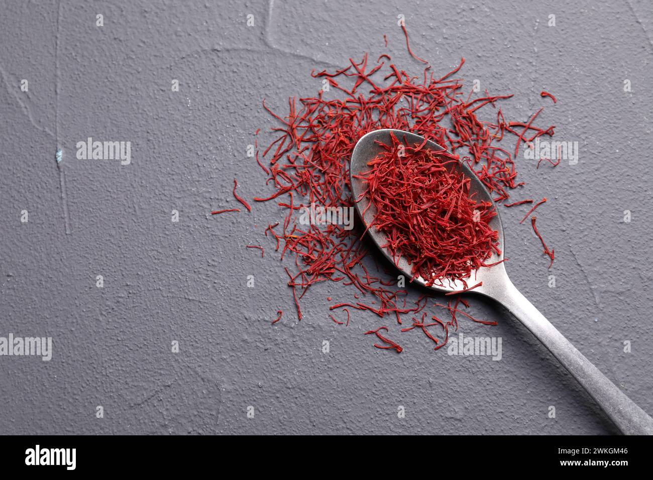 Aromatic saffron and spoon on gray table, top view. Space for text ...