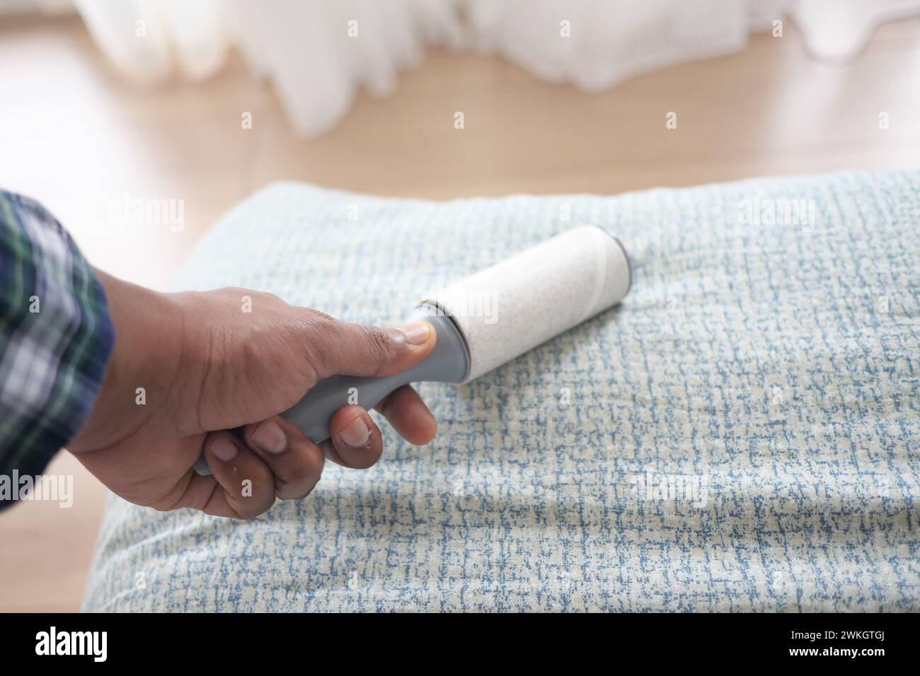 using an adhesive roller to remove lint and fluff from a bed Stock ...