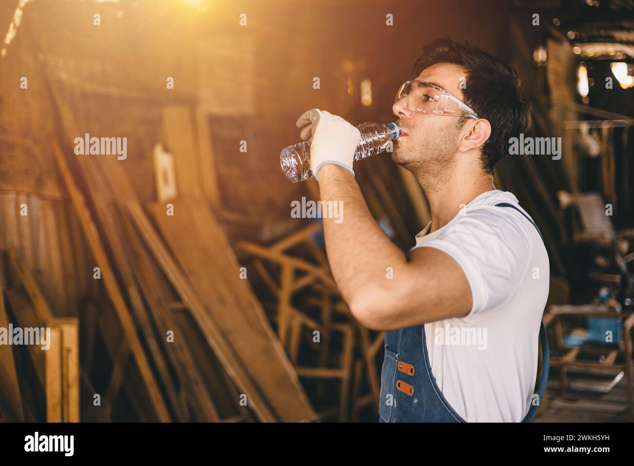 Worker drinking water in an wood industrial factory. Working hydrated ...