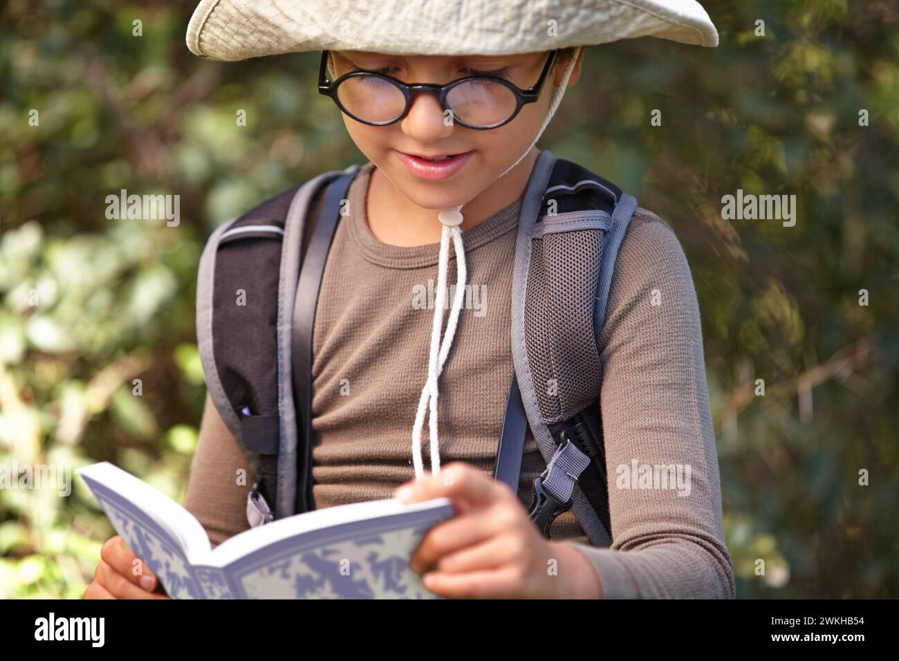 Happy, little boy and reading book in forest for travel guide ...