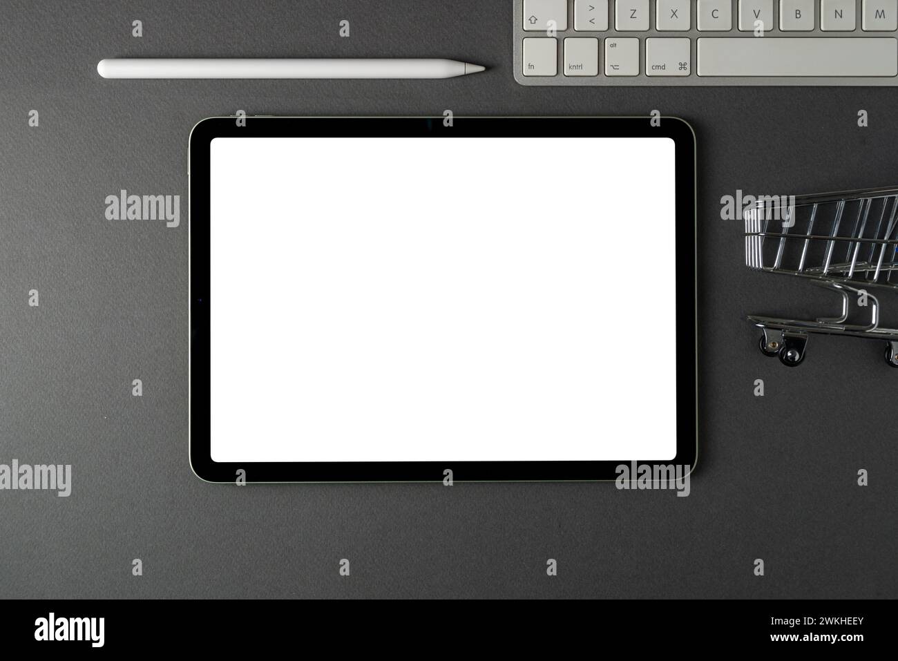 Tablet with blank screen, keyboard and supermarket cart on dark gray ...