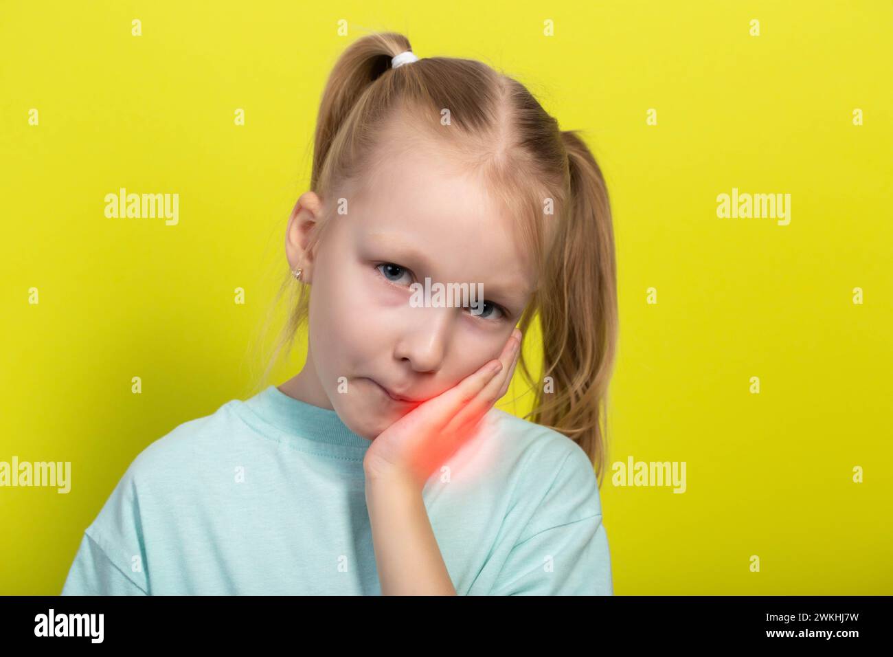 A beautiful little girl of seven years old holds her red, inflamed ...
