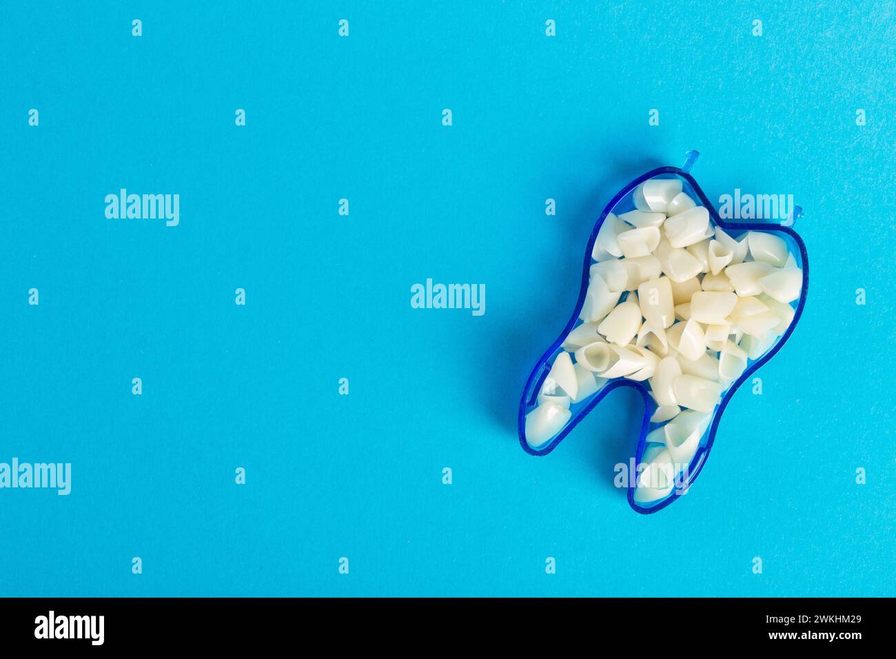 Dental crowns in the shape of a tooth on a blue background. The concept ...