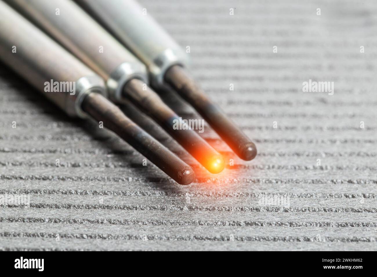 Serviceable modern ceramic glow plugs on a gray background. Orange glow ...