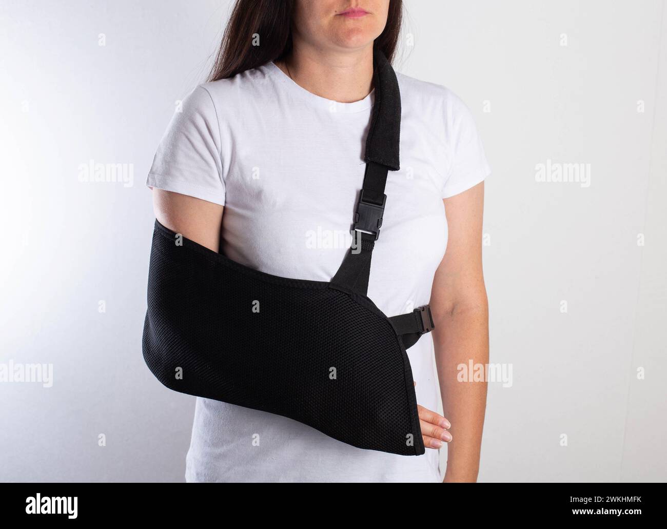 A girl in white with a fixing black bandage on her arm after an injury ...
