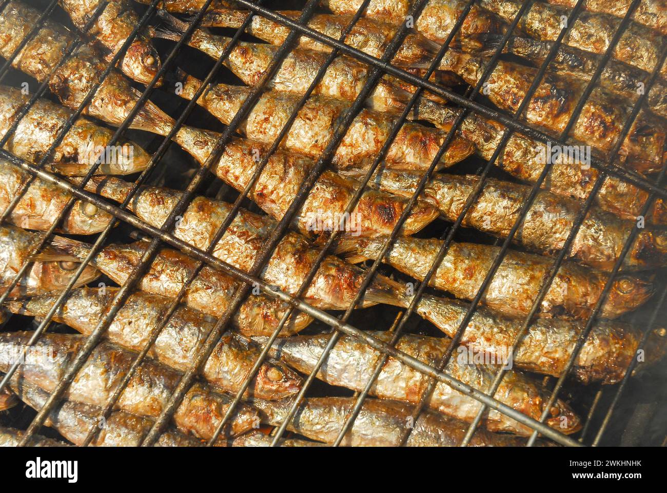 Grilled sardines on a metal grill while grilling on a fire Stock Photo ...