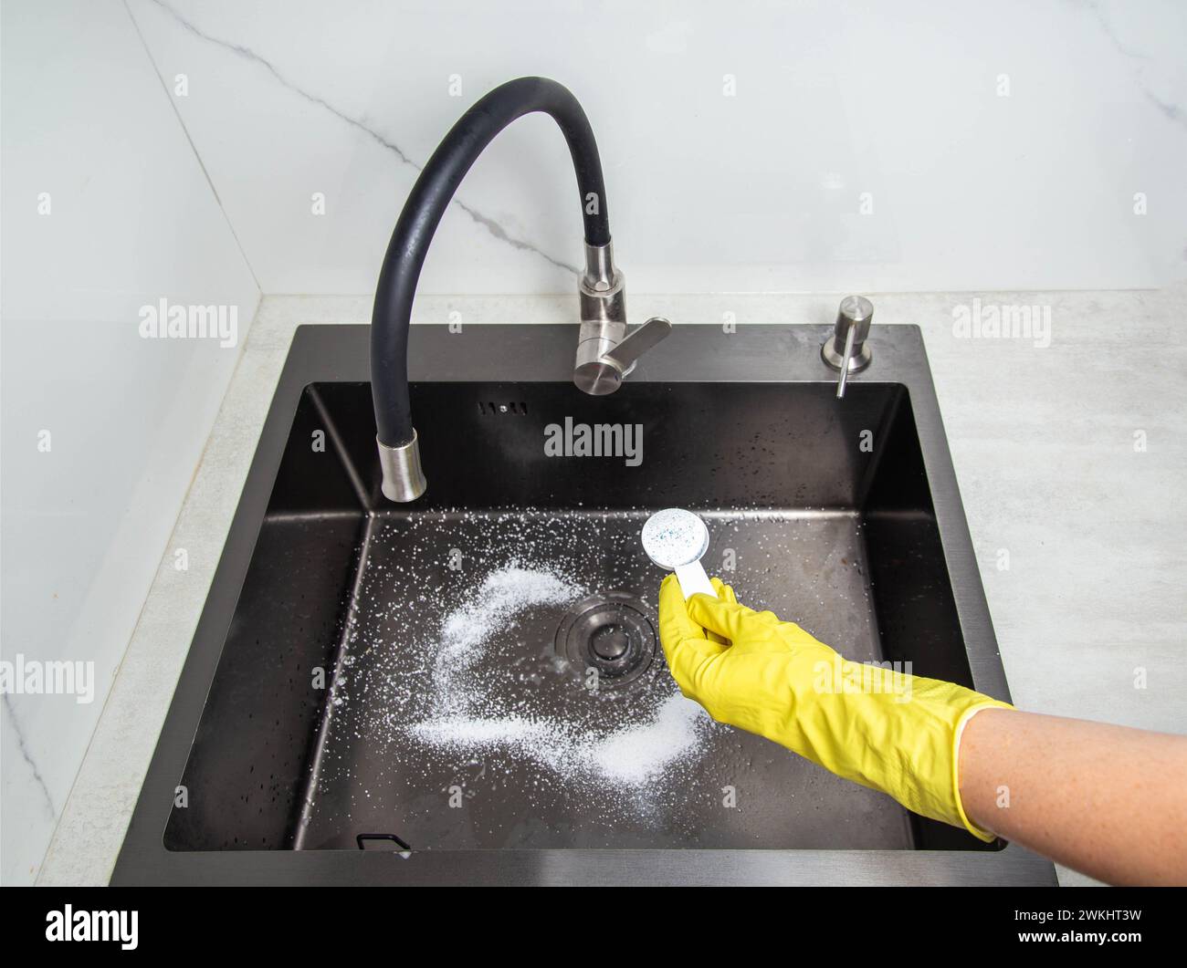A man's hand in a yellow glove holds a spoon with oxygen bleach against ...