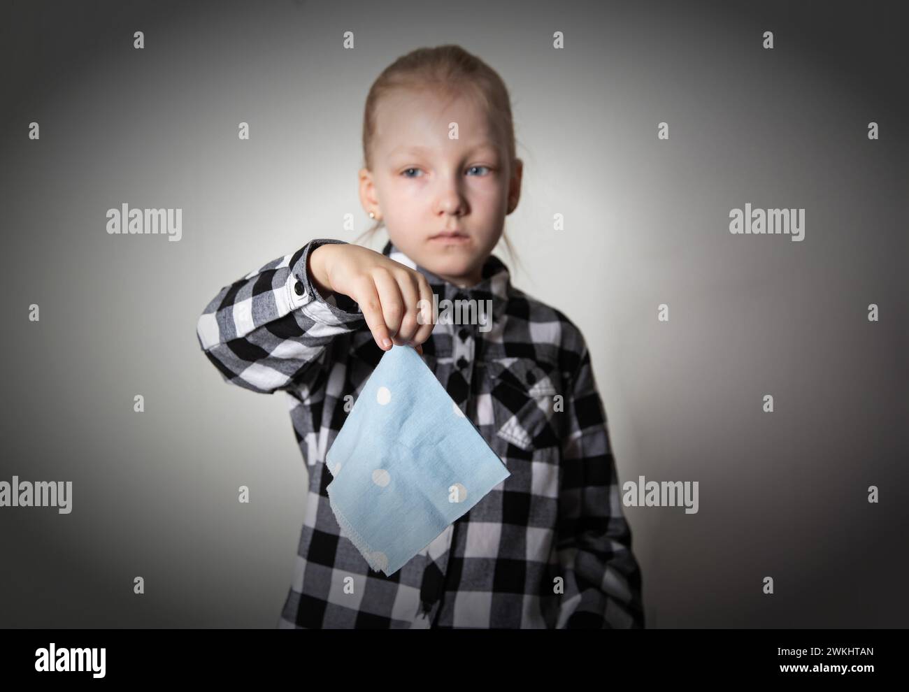 a sad girl aged seven years old holds a handkerchief in her hand ...