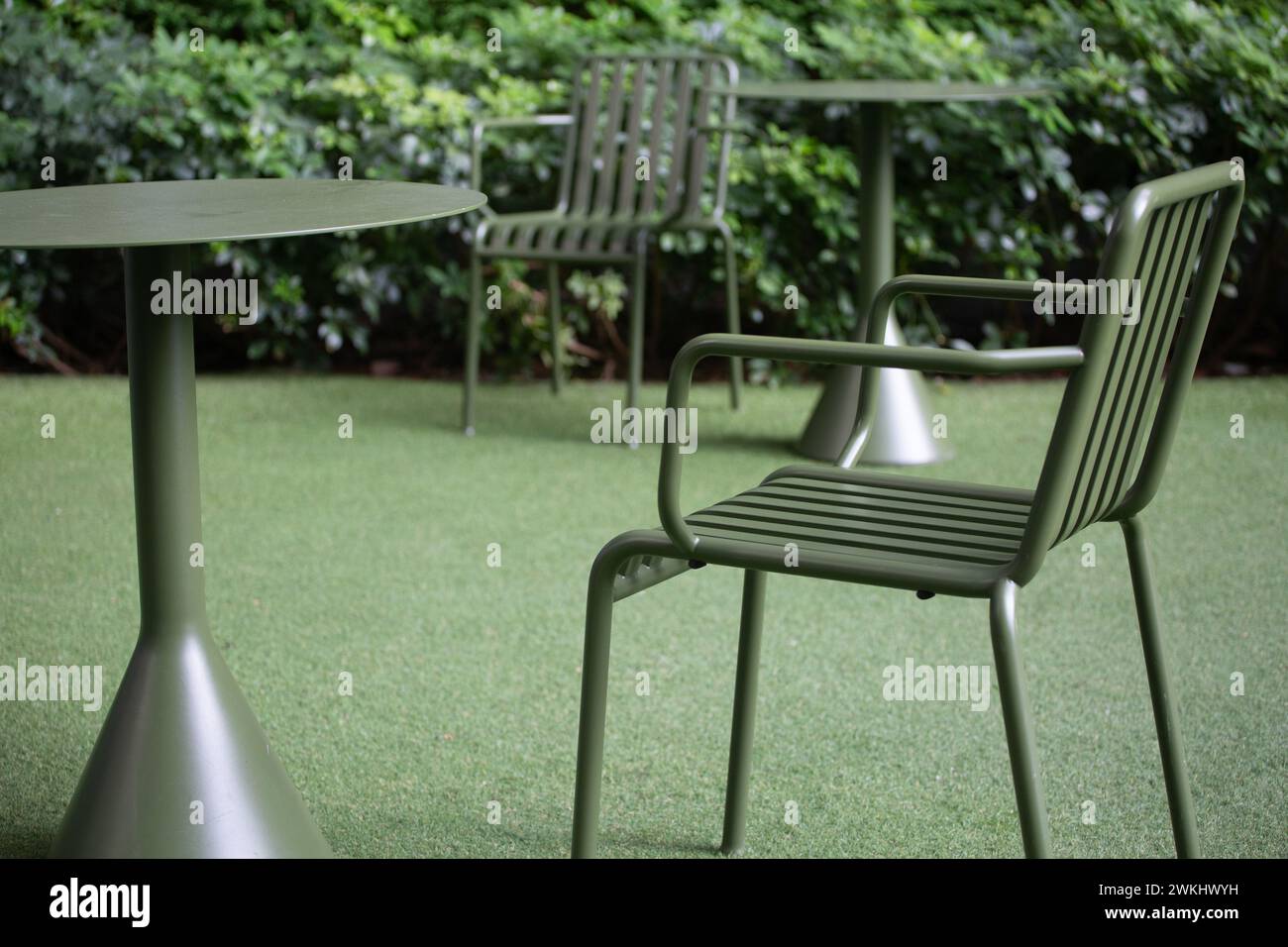 Two Green tables, two green chairs, green carpet at a greenery outdoor ...