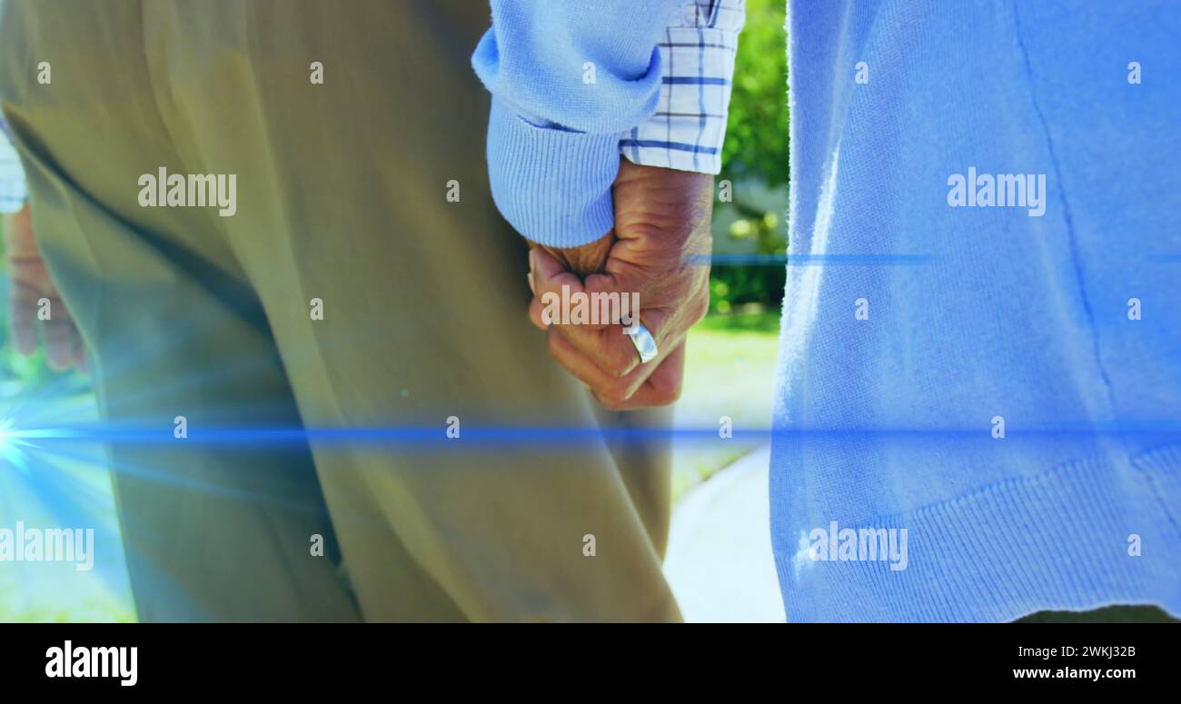 Image of light moving over midsection of senior couple walking holding ...
