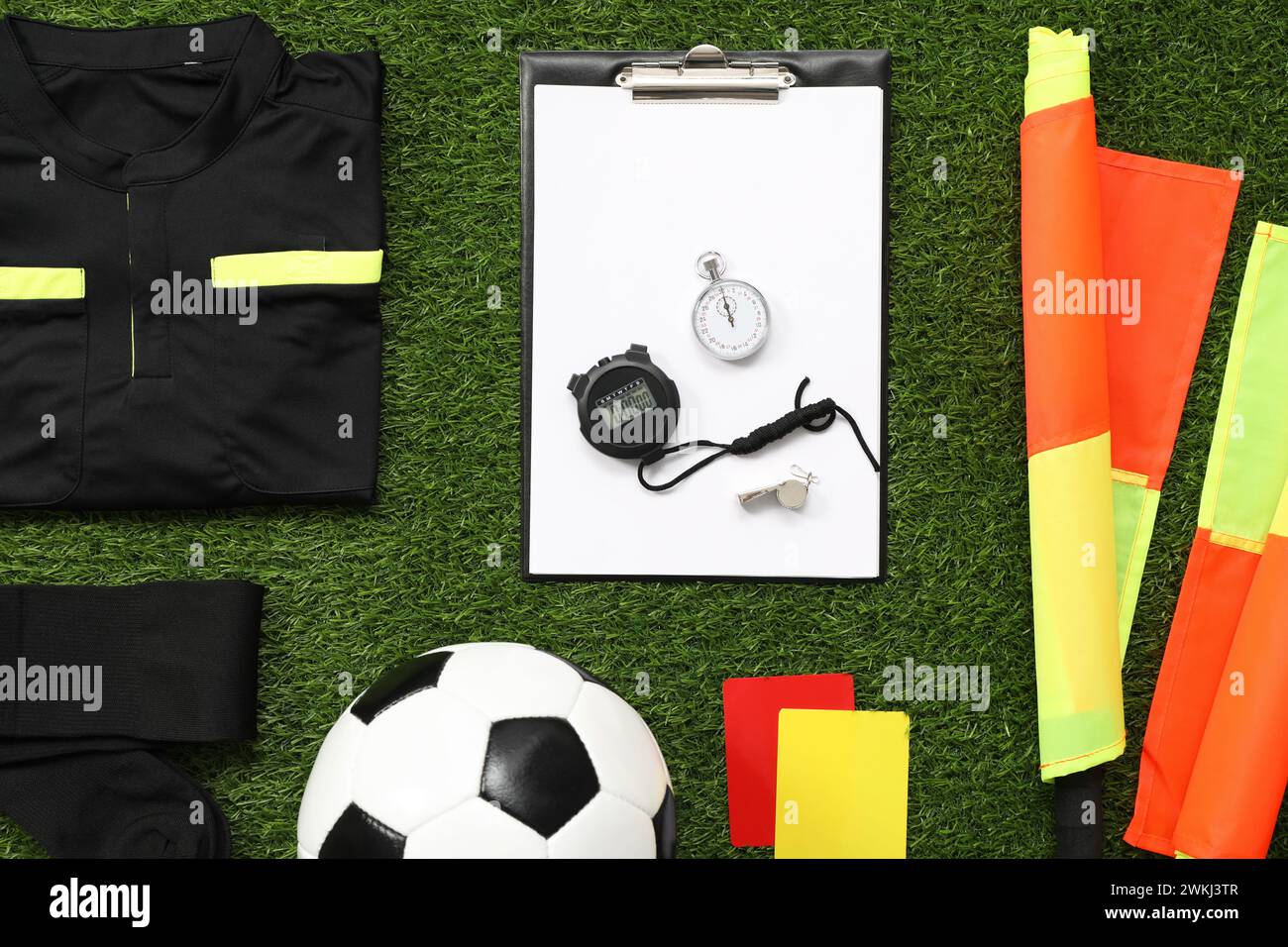 Uniform, soccer ball and other referee equipment on green grass, flat ...