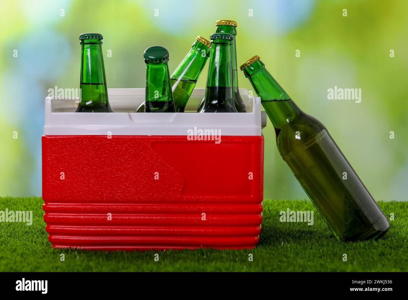 Plastic cool box with glasses of drink on artificial grass, closeup ...