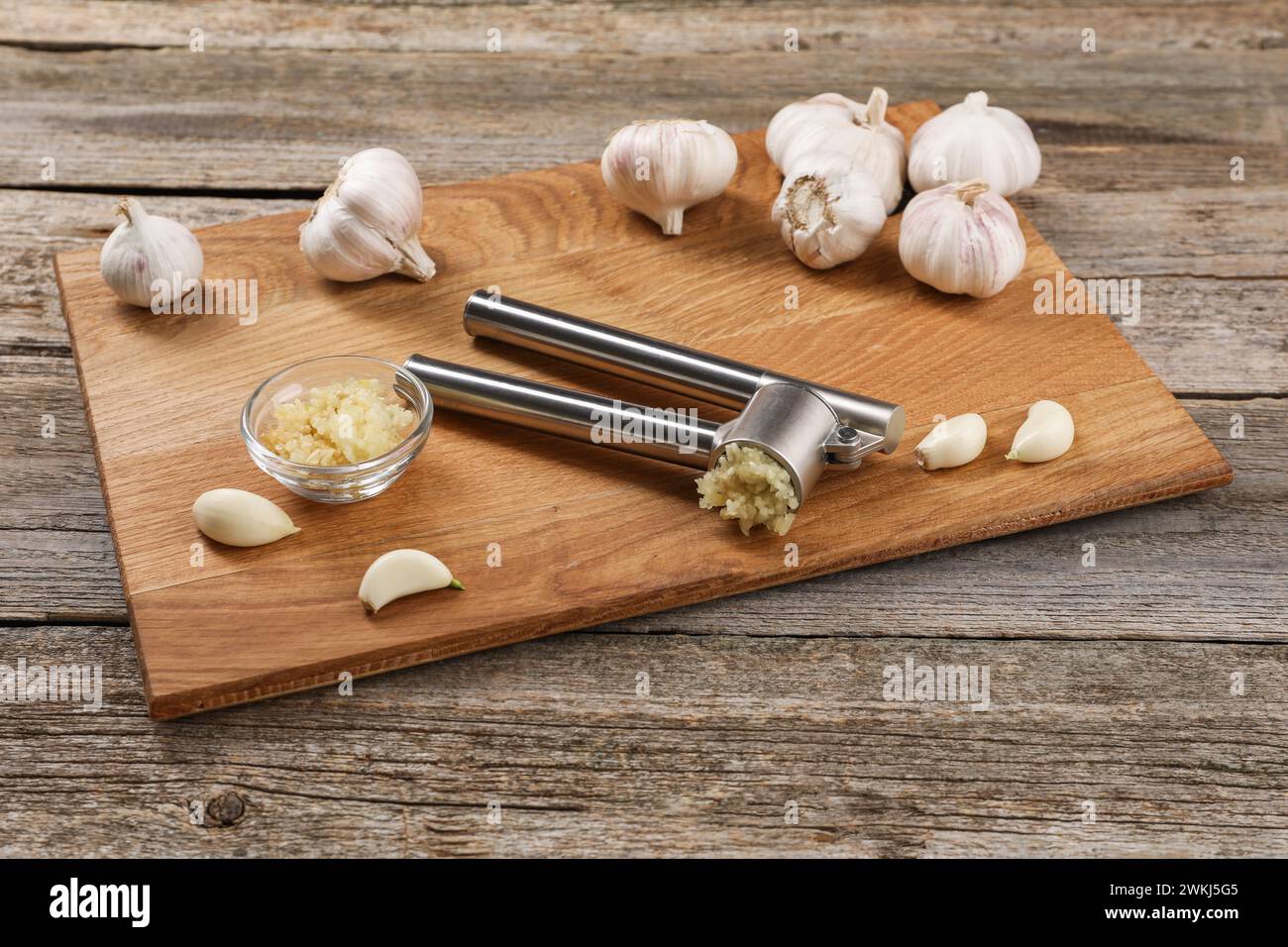 Garlic press, cloves and mince on wooden table. Kitchen utensil Stock ...