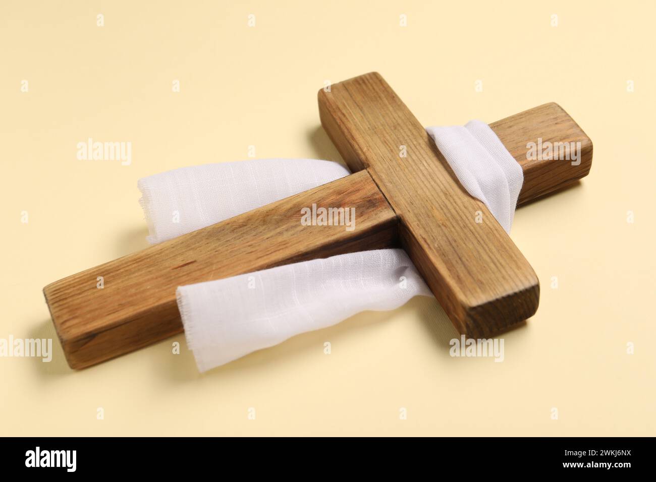 Wooden cross and white cloth on beige background. Easter attributes ...