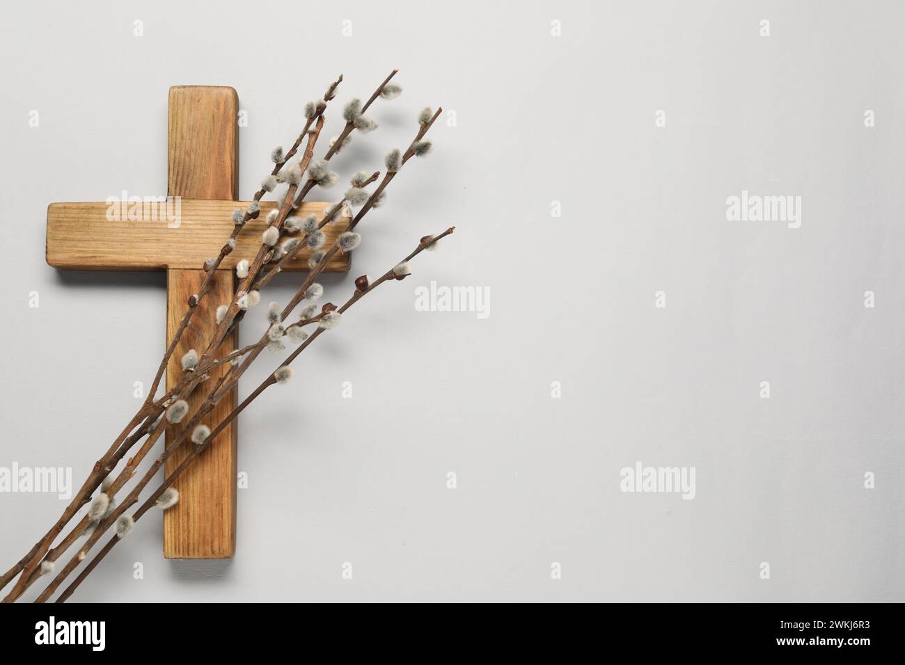 Wooden cross and willow branches on light grey background, top view ...