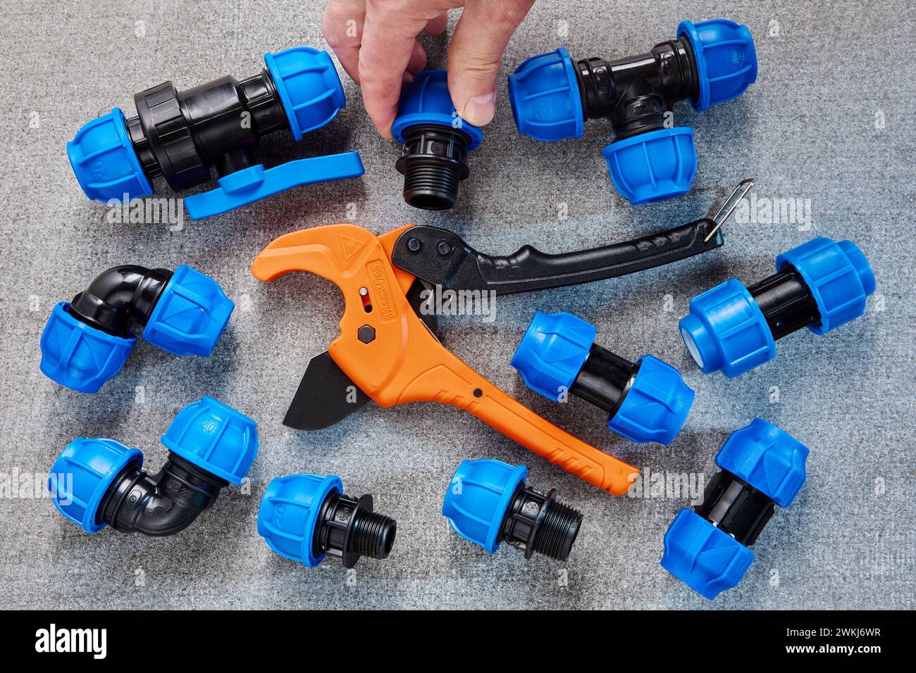 Hand of plumber choosing compression fitting for connecting HDPE pipes ...