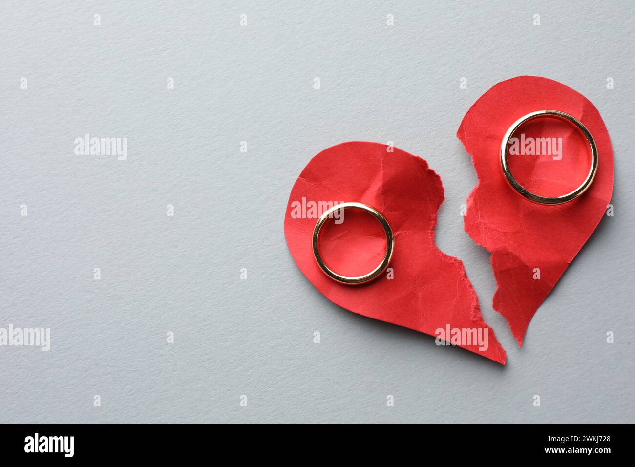 Broken heart. Halves of torn red paper heart and wedding rings on white ...