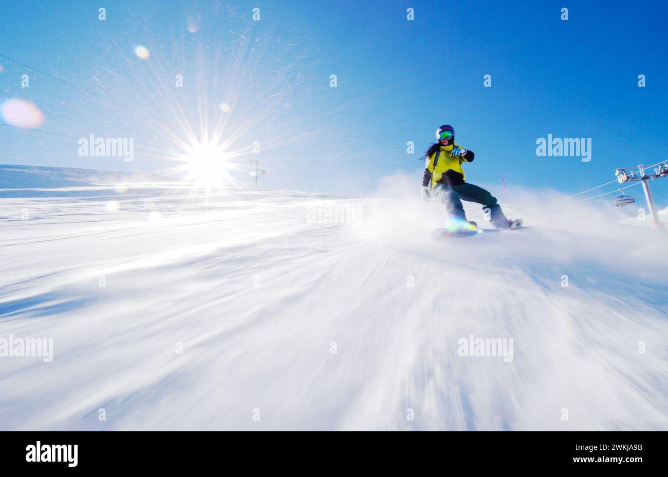Girl snowboarding on slopes. Sun rays and flare visible Stock Photo - Alamy