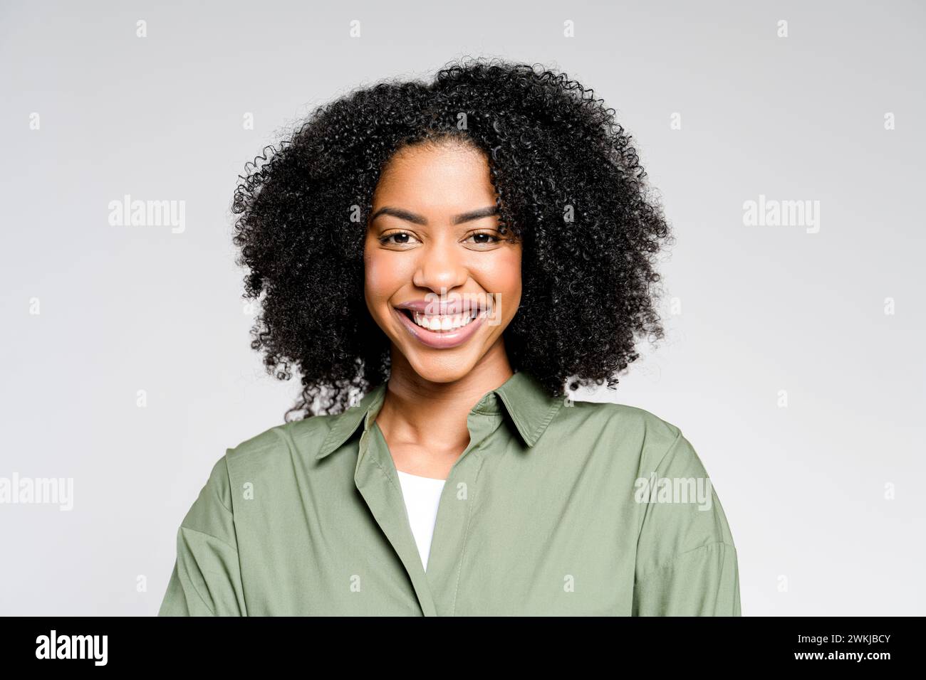 A cheerful African-American woman in a smart-casual olive shirt poses ...