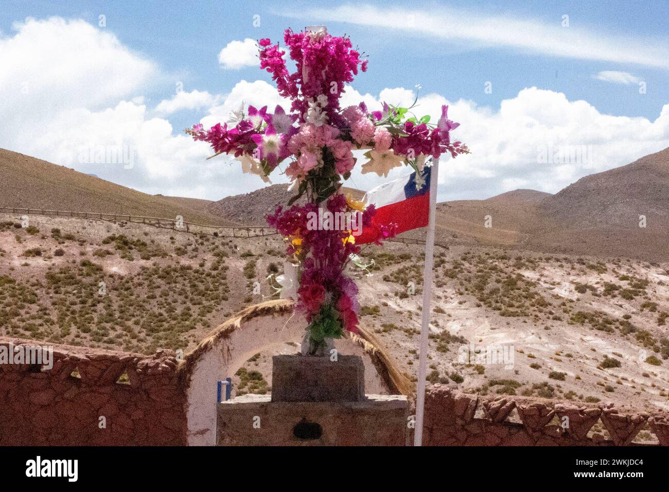 Flower decorated crucifix outside an old church in the Atacama Desert ...