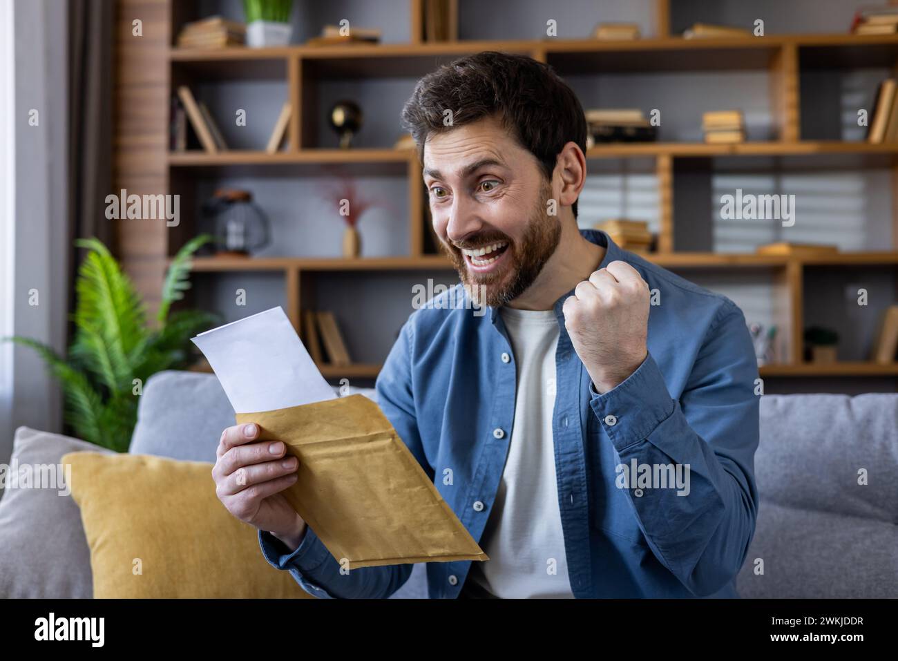 Joyful adult male sitting on couch, feeling elated as he looks at a ...