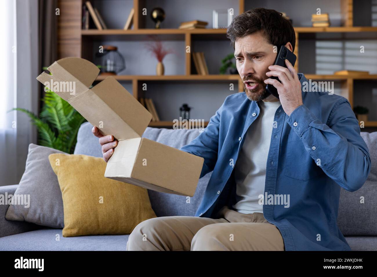 An upset man discovers his cardboard box is empty as he talks on the ...
