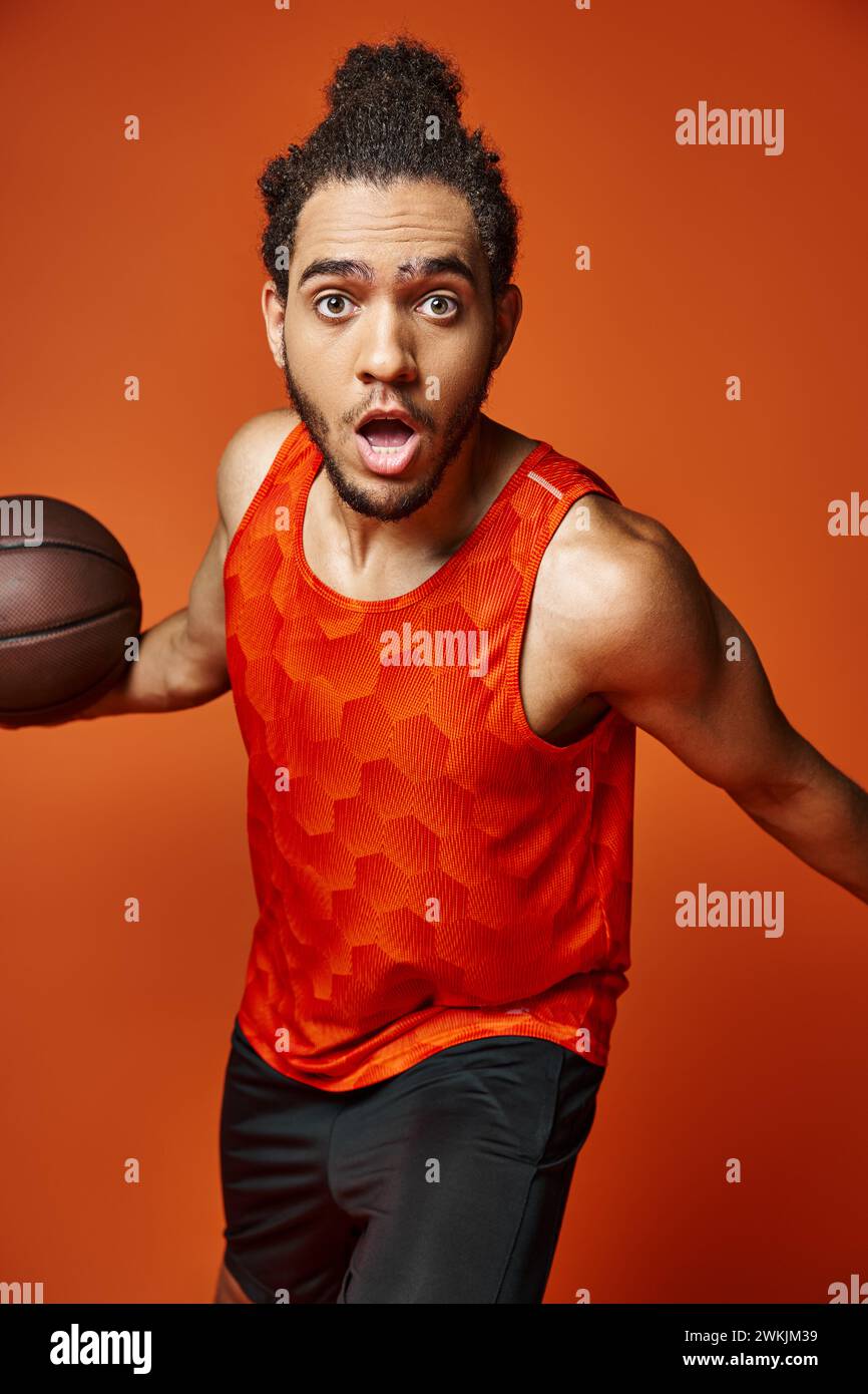 shocked handsome african american man in sportwear playing basketball ...