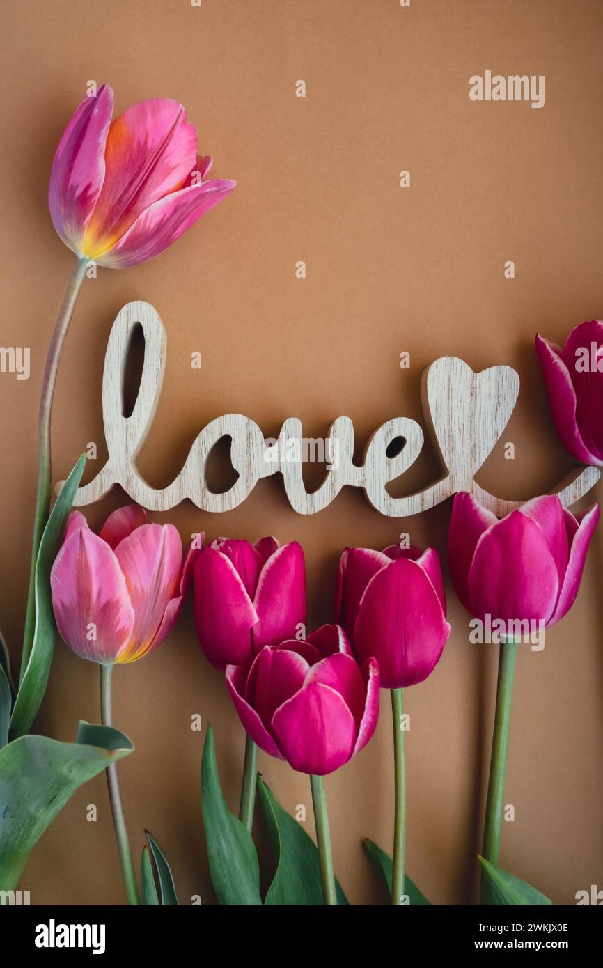 Wooden word LOVE message text. Beautiful pink tulip flowers around on ...