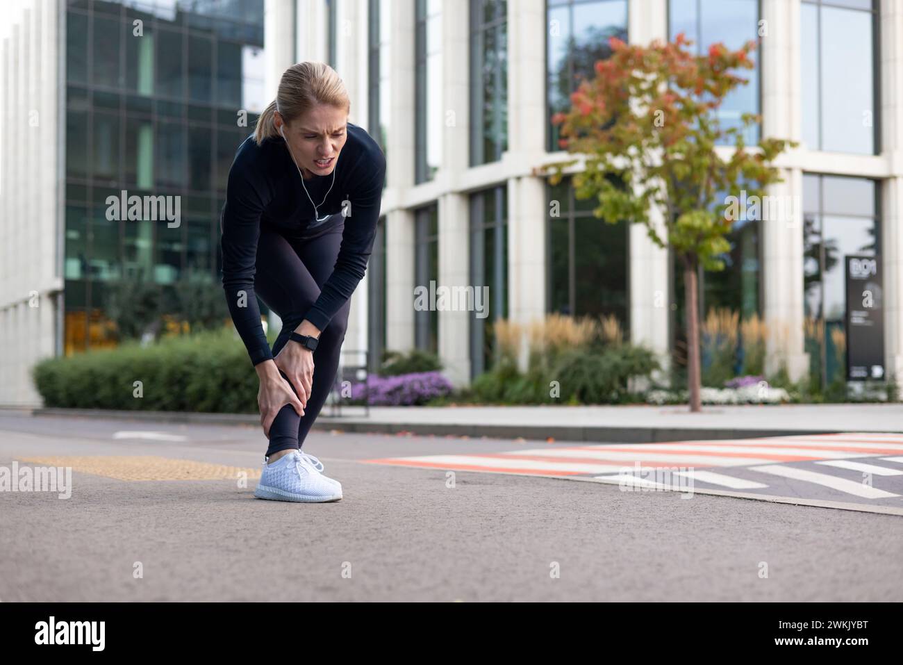 Athletic woman in pain holding her shin, showing signs of injury while ...