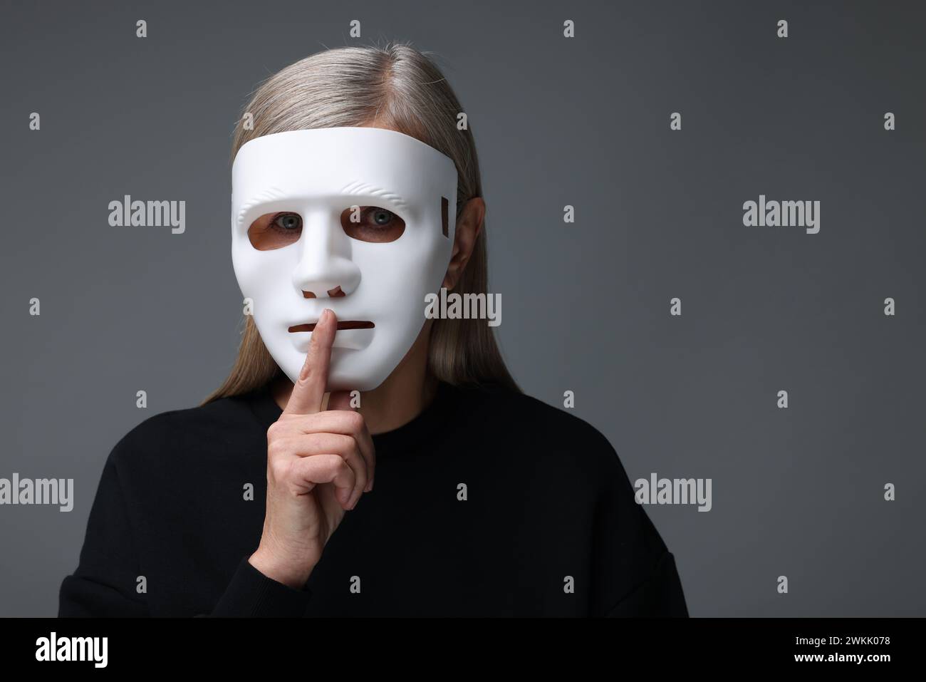 Multiple personality concept. Woman in mask showing hush gesture on ...