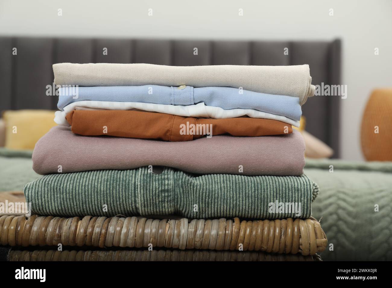Sorting and organizing. Stack of different folded clothes on wicker ...