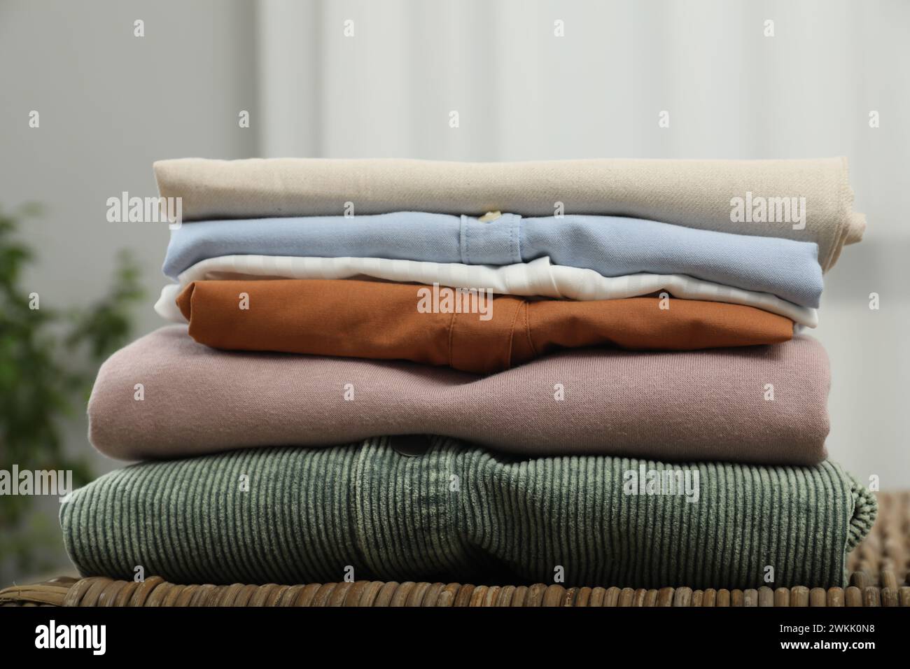 Sorting and organizing. Stack of different folded clothes on wicker ...