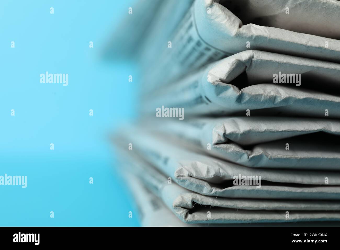 Stack of newspapers on light blue background, closeup. Journalist's ...