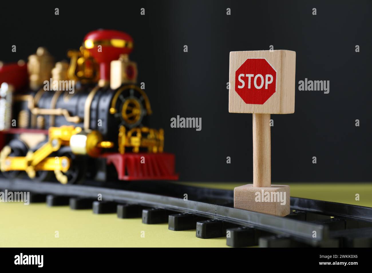 Road Stop sign as barrier blocking way for toy train on yellow surface ...