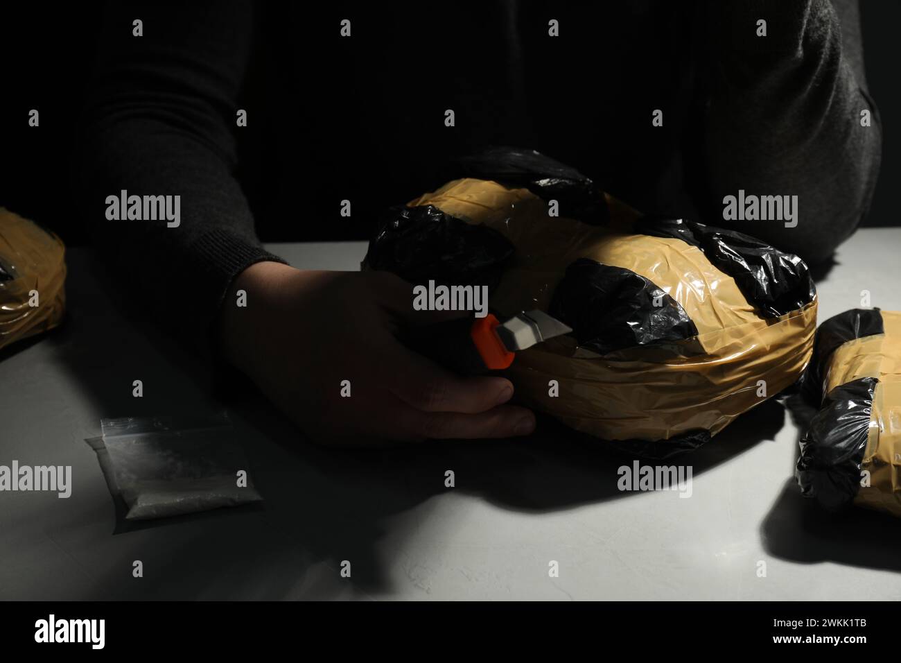 Smuggling and drug trafficking. Man opening package of narcotics with ...