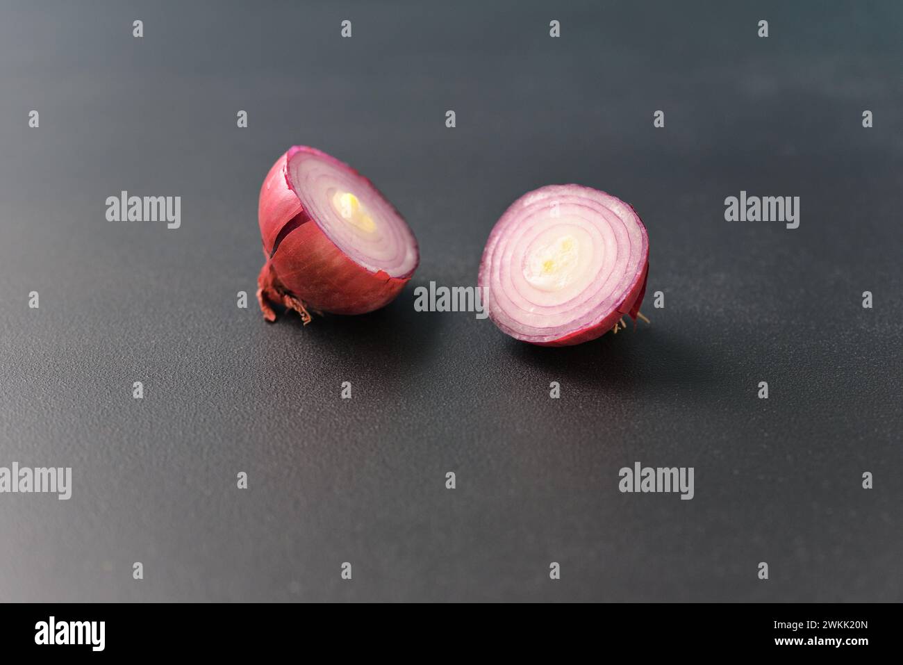 Red onion cut in half on dark background Stock Photo - Alamy