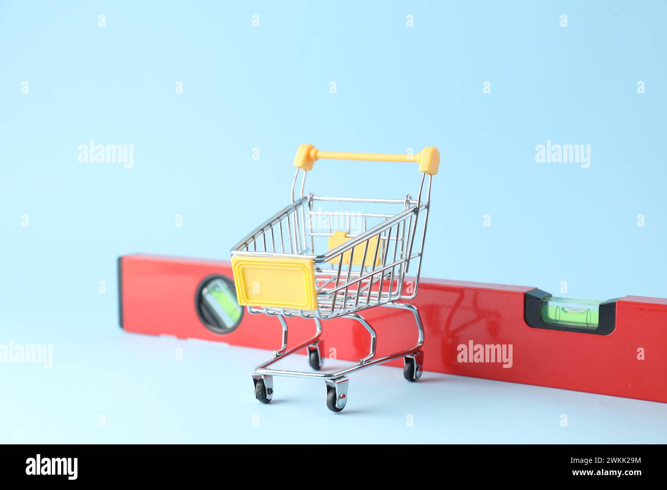 Measure level and empty shopping cart on light blue background Stock ...