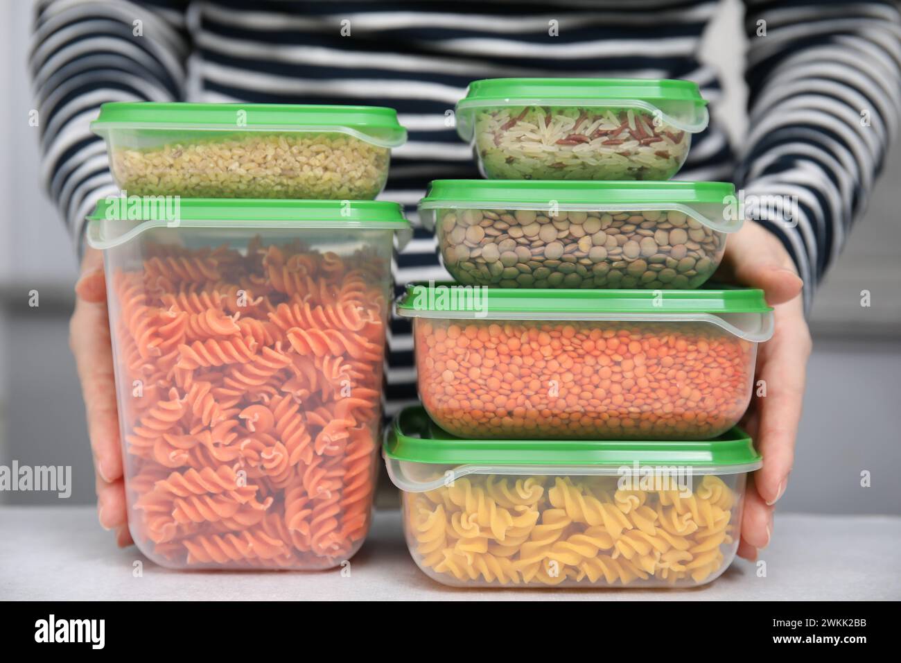 Woman with plastic containers filled of food products at light table ...