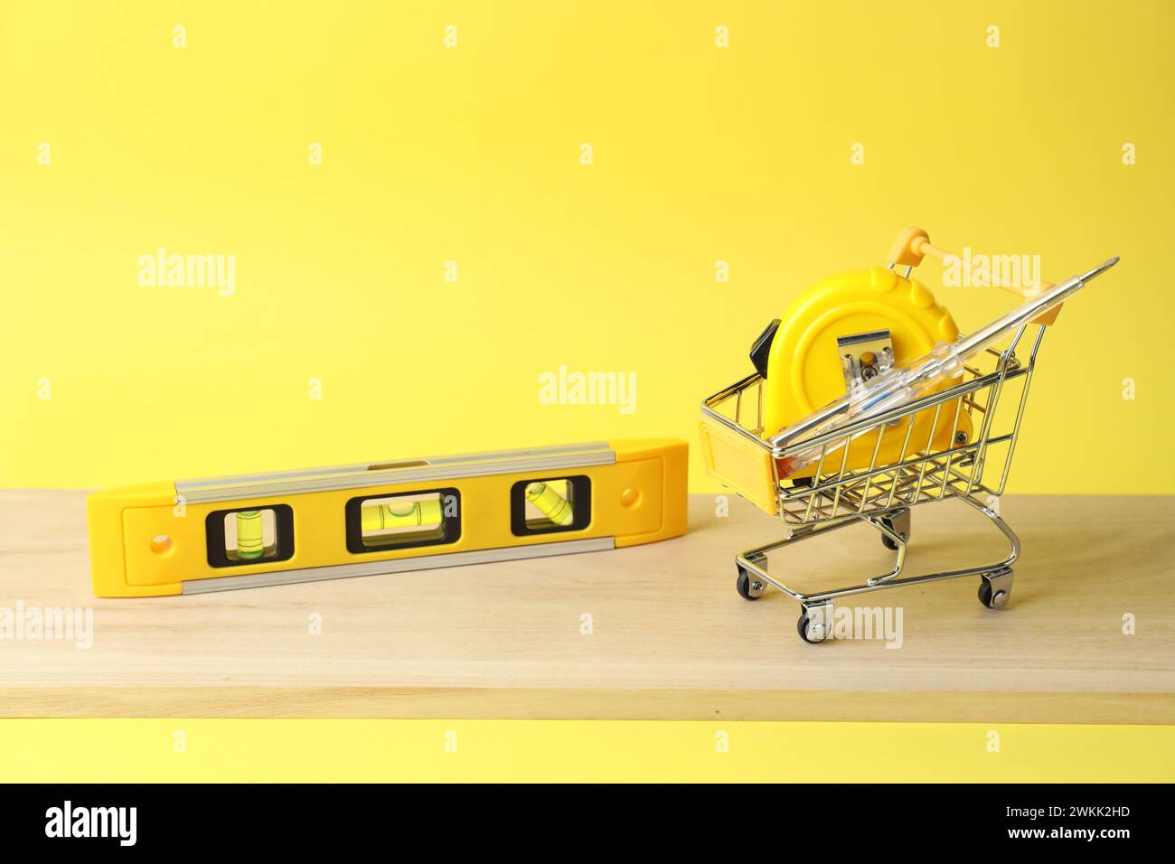 Small shopping cart and set of construction tools on yellow background ...
