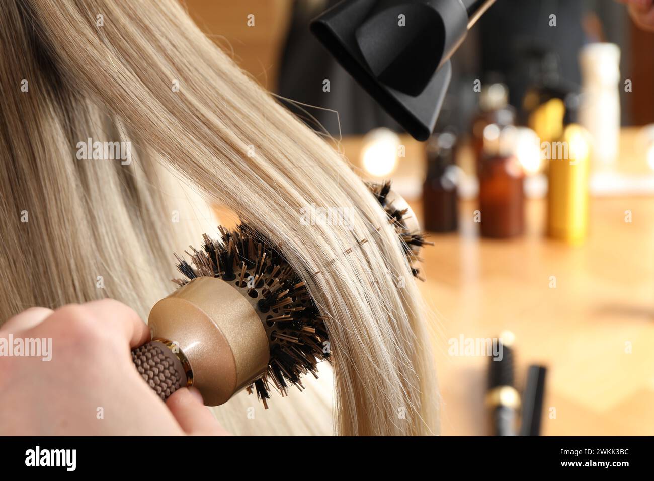 Hairdresser blow drying client's hair in salon, closeup Stock Photo - Alamy