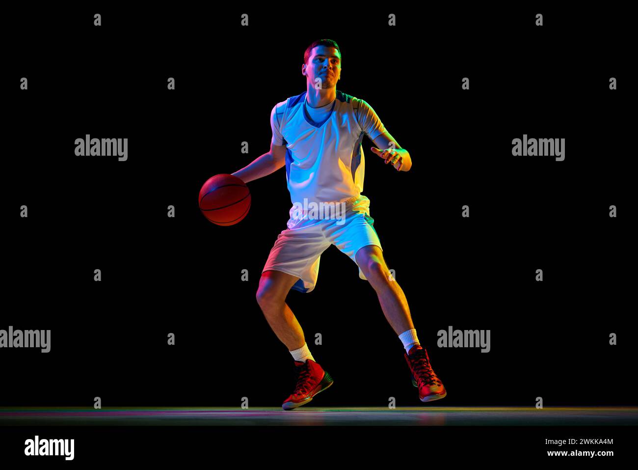 Focused basketball player, performs double ball technique in motion ...