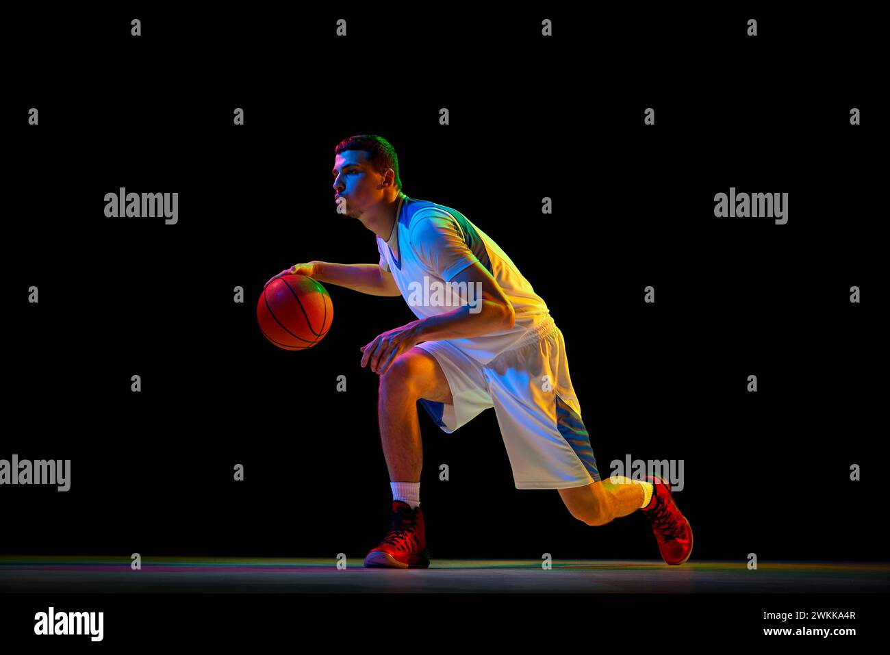 Young, focused basketball player performs low-handling technique with ...