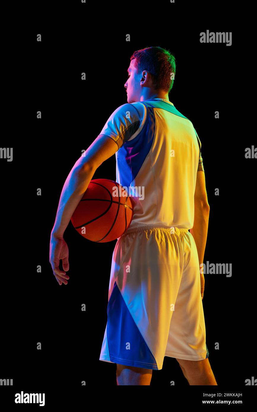 Rear view portrait of basketball player in uniform holds ball against ...