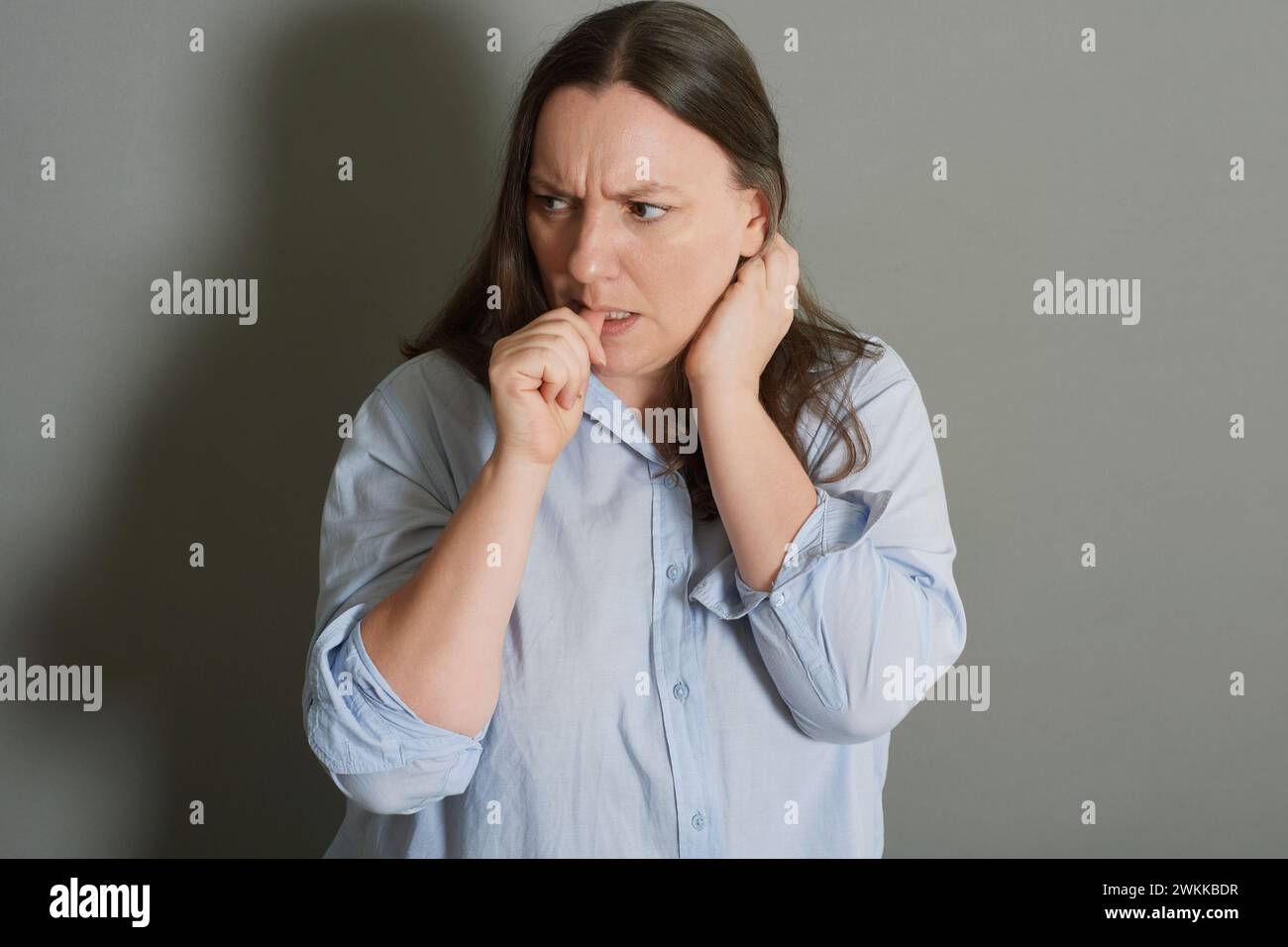 Studio portrait of scared woman biting her nails, fear and insecurities ...