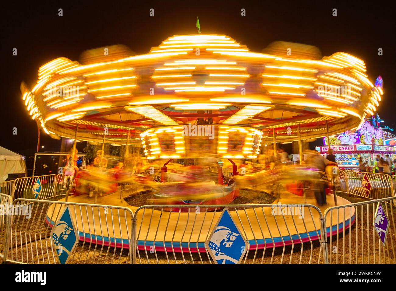 Vibrant Carousel Motion Blur at Nighttime Fair with Funnel Cake Stand ...
