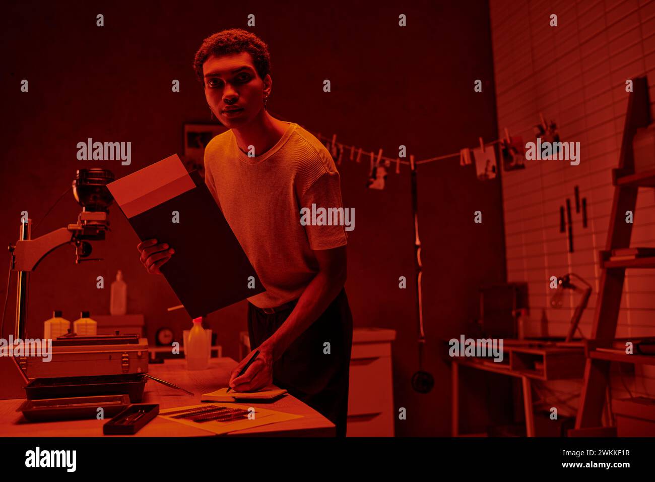 young photographer prepares photographic paper for printing and taking ...