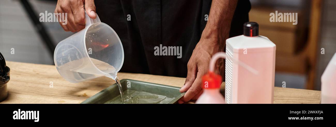 cropped dark skinned man preparing film development solution in ...
