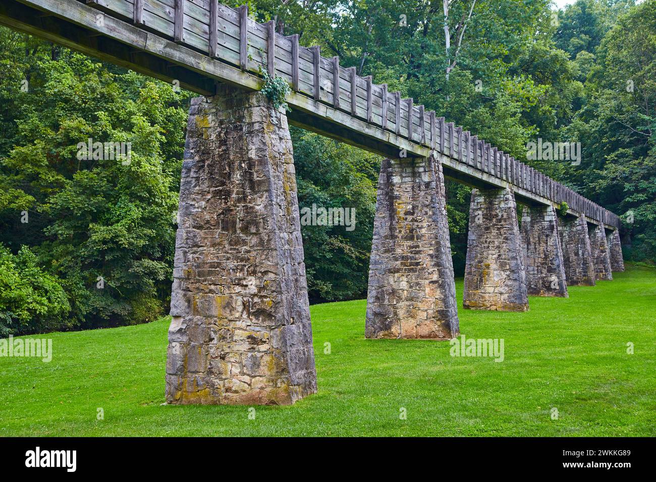 Historical Wooden Trestle Bridge with Stone Pillars in Lush Greenery ...