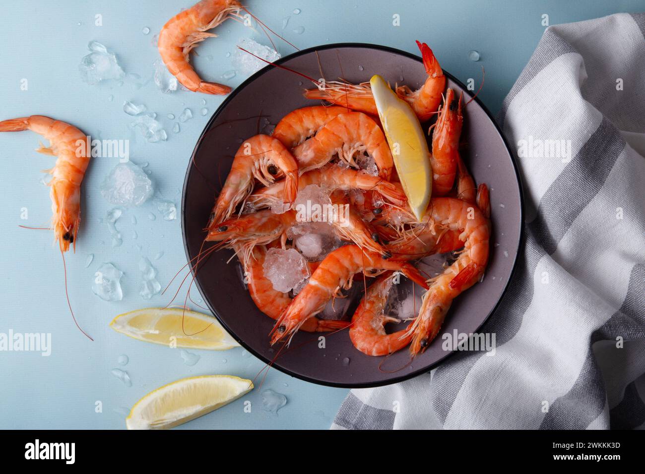 Bowl full of succulent cooked prawns with lemon on blue background with ...